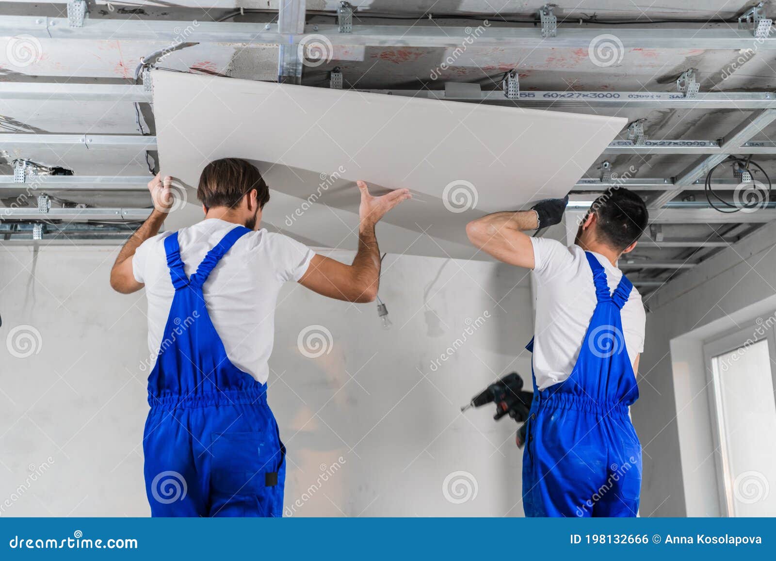 Builders in Blue Overalls Making Ceiling in Apartment Room Stock Photo ...