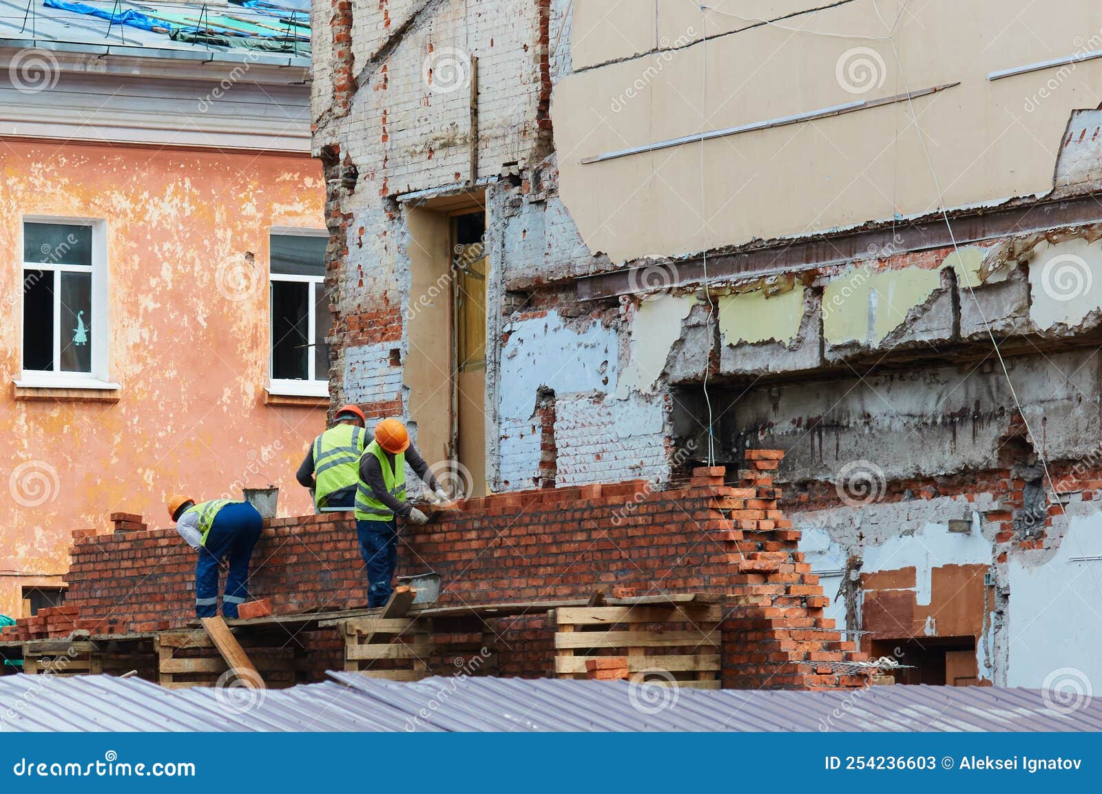 Builders in Overalls and Hard Hats Laying Red Bricks at a Construction ...