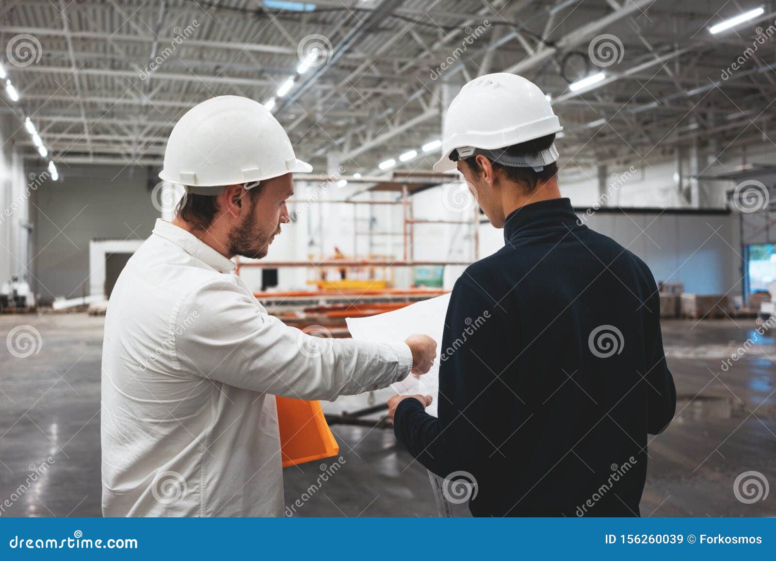 Building Industry. Young Engineer Discussing with Building Worker on ...