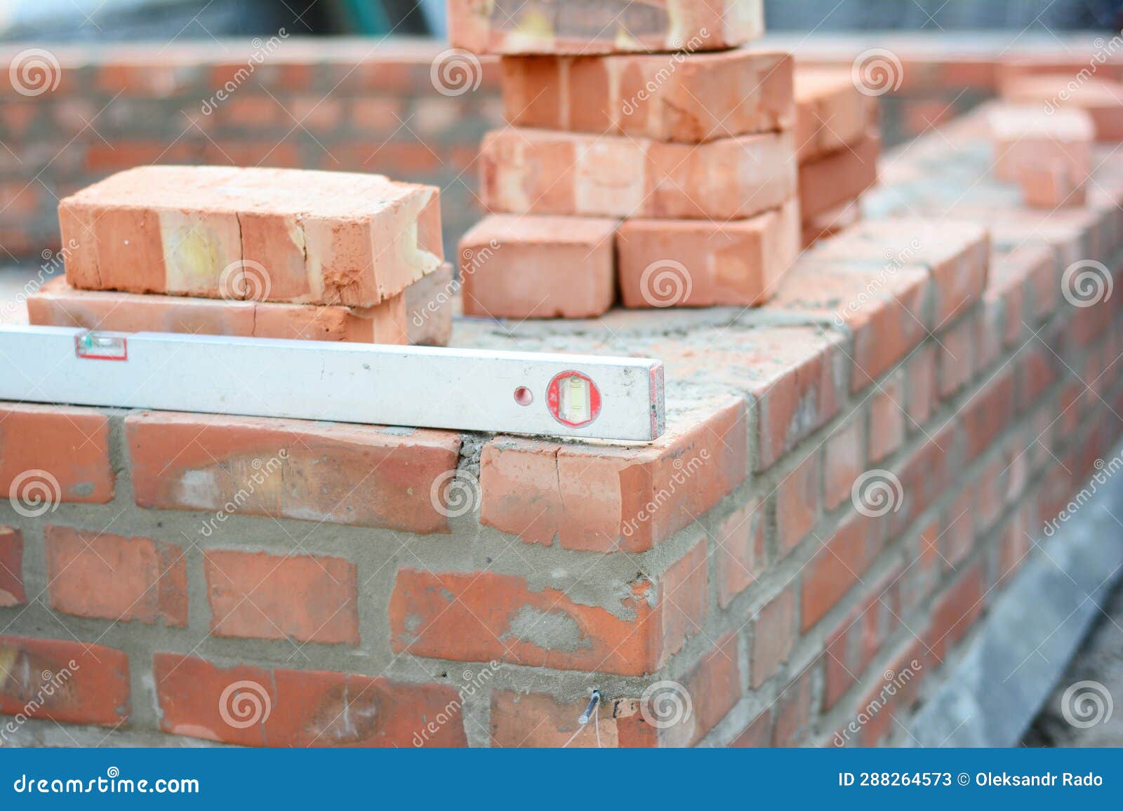 Building Red Brick House Wall with Spirit Level and Pile of Bricks ...