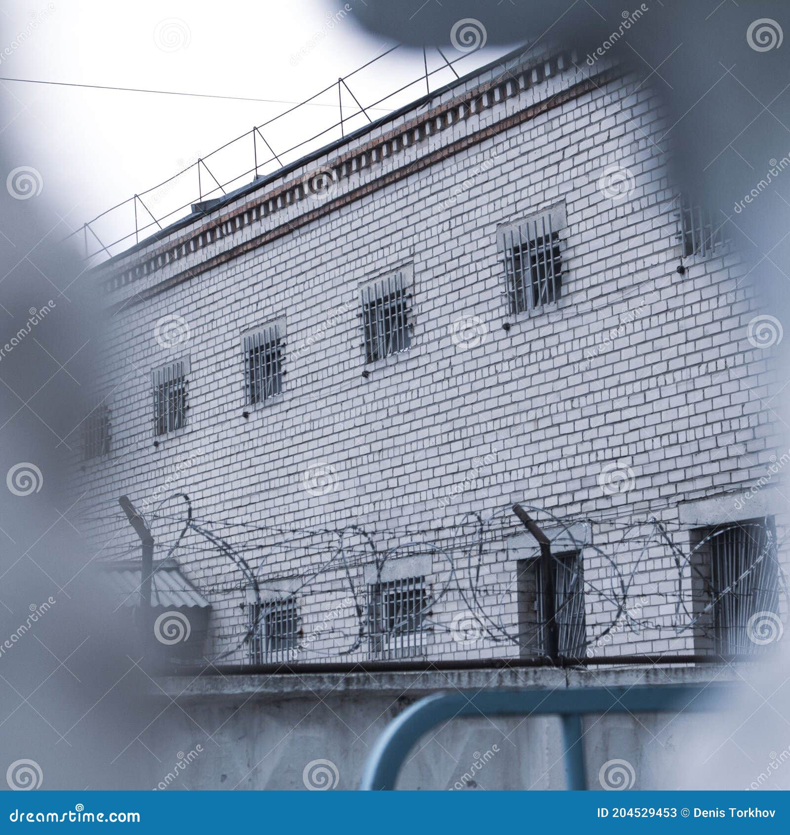 A Building Surrounded by Barbed Wire and Bars on the Windows Visible ...