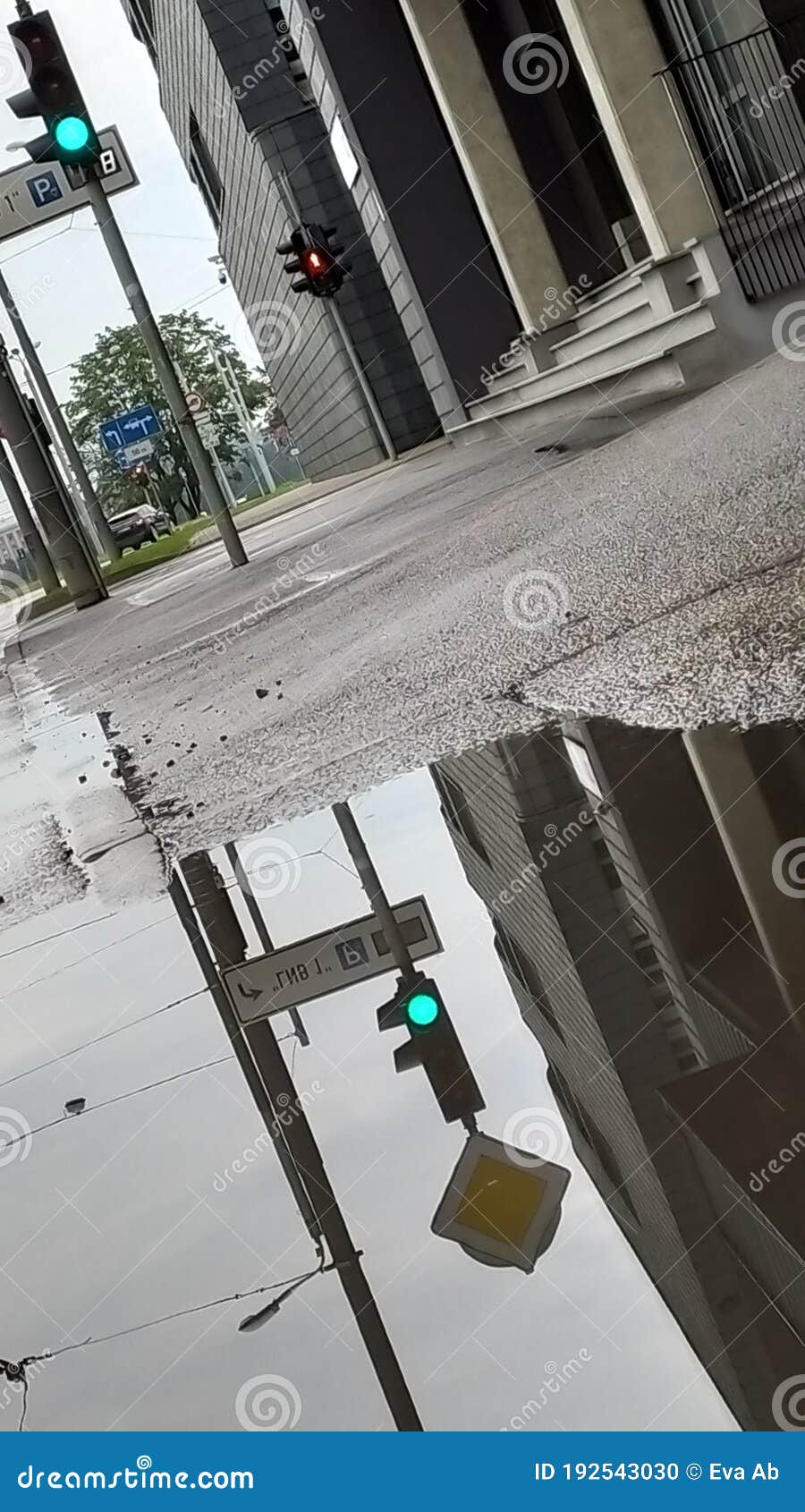 Building And Traffic Light In Reflection In A Puddle On The Pavement ...