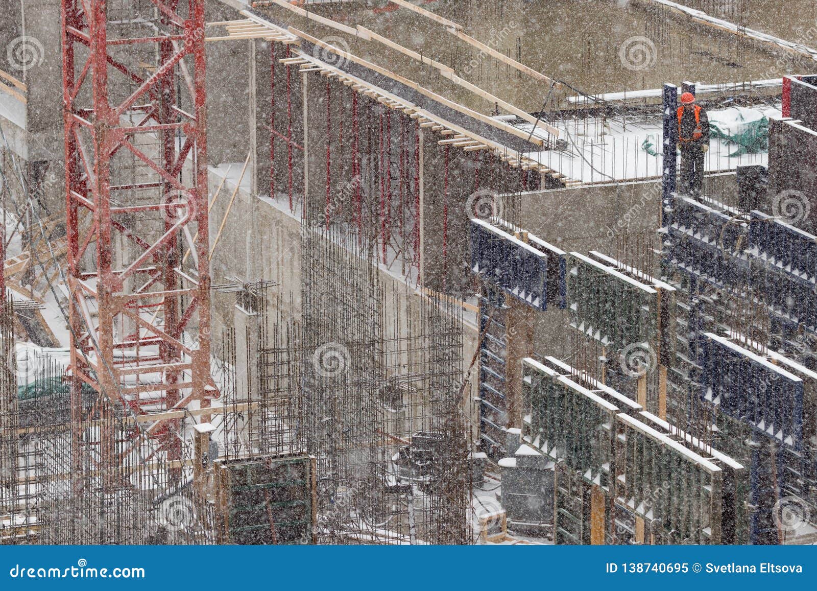 Building Under Construction in a Snowfall. Worker Stands on the Edge of ...