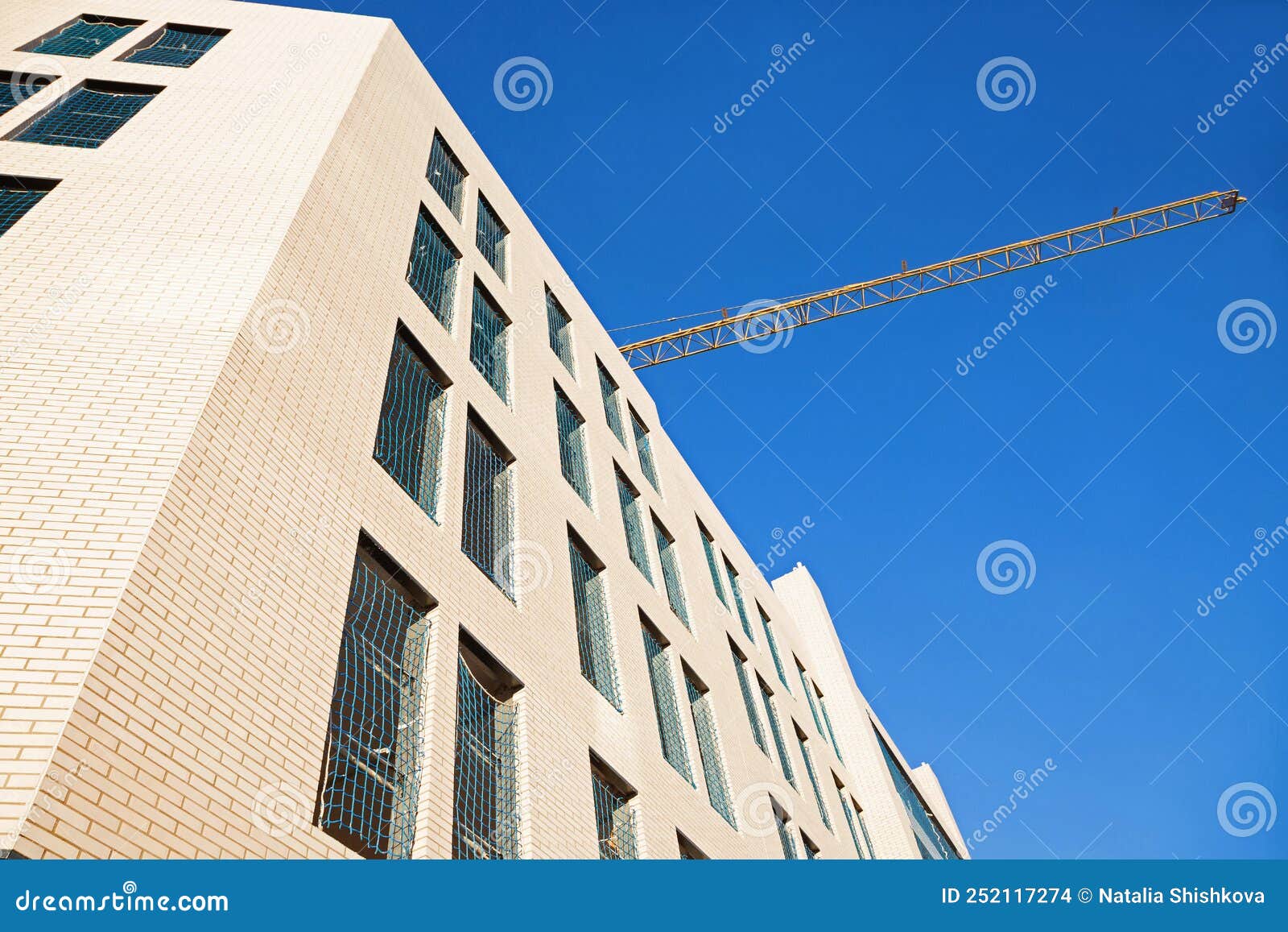 A Building Under Construction with Windows and Crane are Against a Blue ...