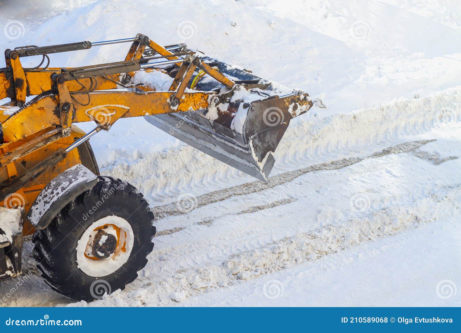 A Bulldozer with a Bucket Clears Snow from the Road in Winter after a ...
