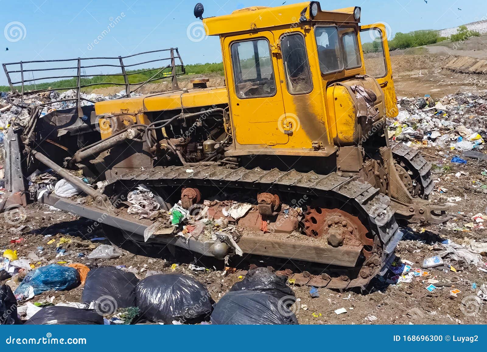 A Bulldozer Clears Heaps of Garbage in a Garbage Can. Work Bulldozer in ...