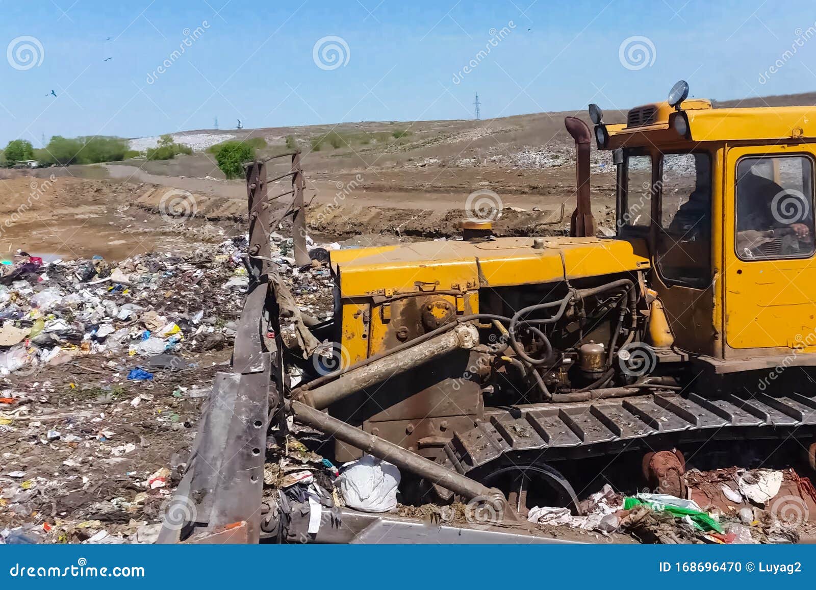 A Bulldozer Clears Heaps of Garbage in a Garbage Can. Work Bulldozer in ...