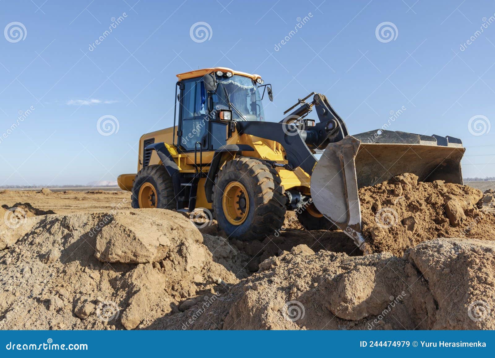 Bulldozer or Loader Moves the Earth at the Construction Site Against ...