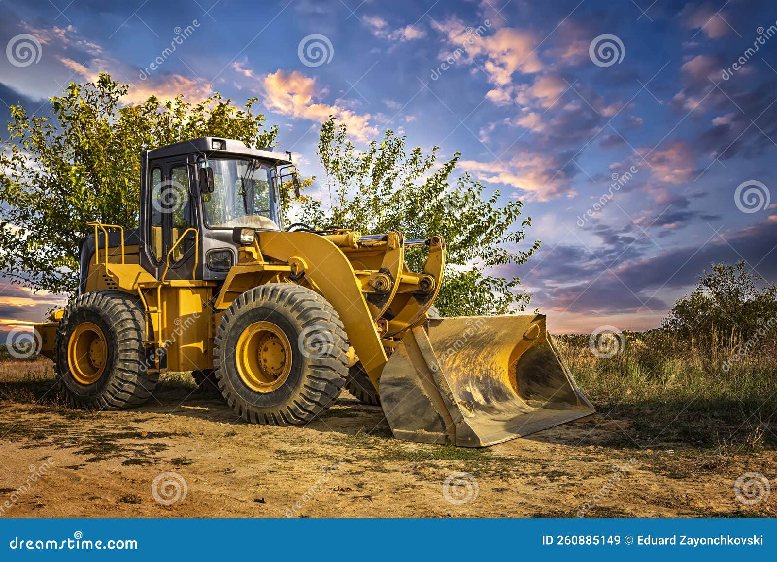 A Bulldozer or Loader Moves the Earth at the Construction Site Against ...