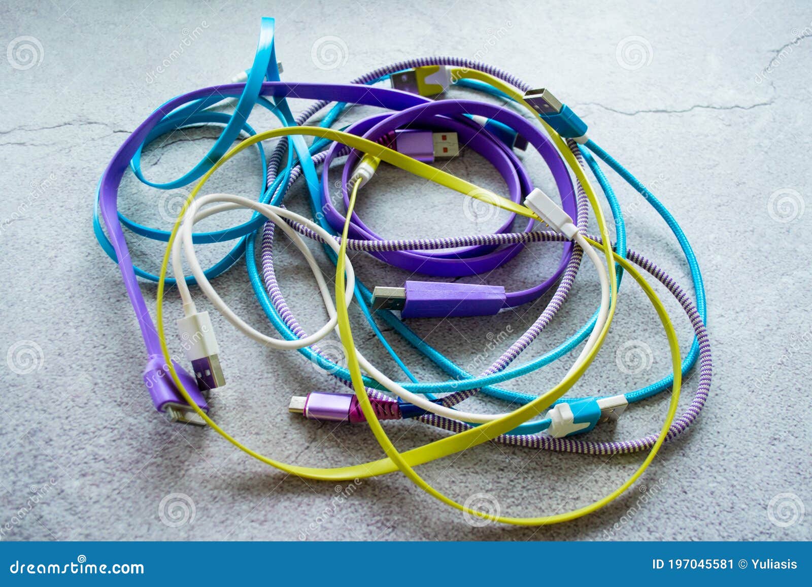 A Bunch of Colored Wires for Charging Gadgets on a Gray Concrete ...