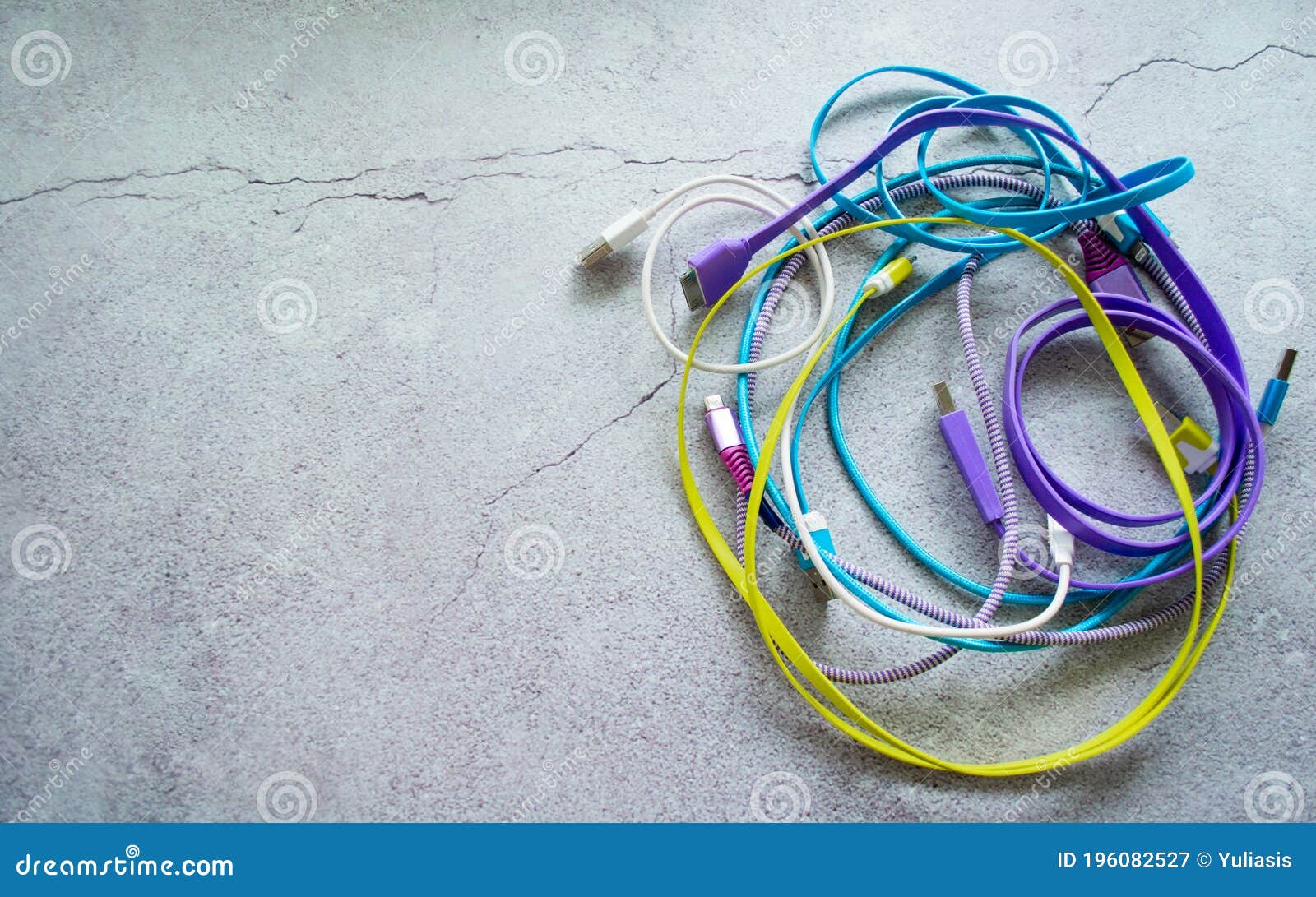 A Bunch of Colored Wires for Charging Gadgets on a Gray Concrete ...