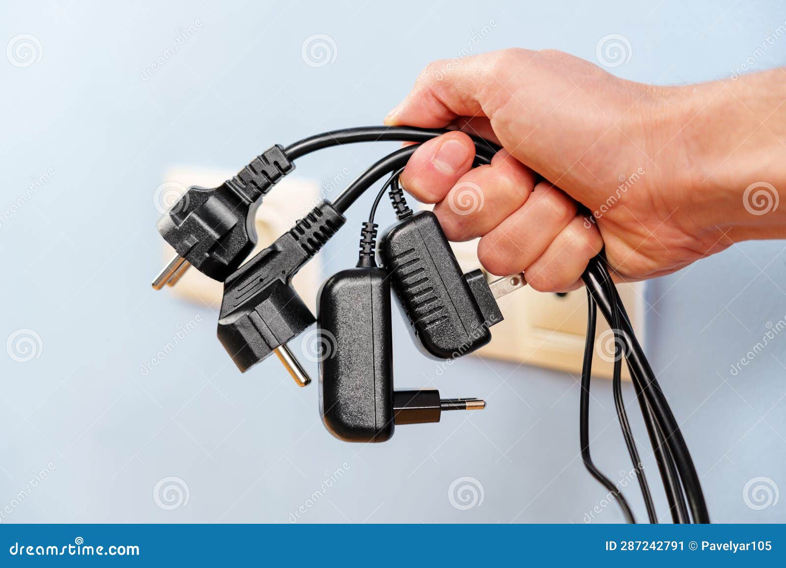 A Bunch of Disconnected Electrical Plugs with Cables in a Hand in Room ...