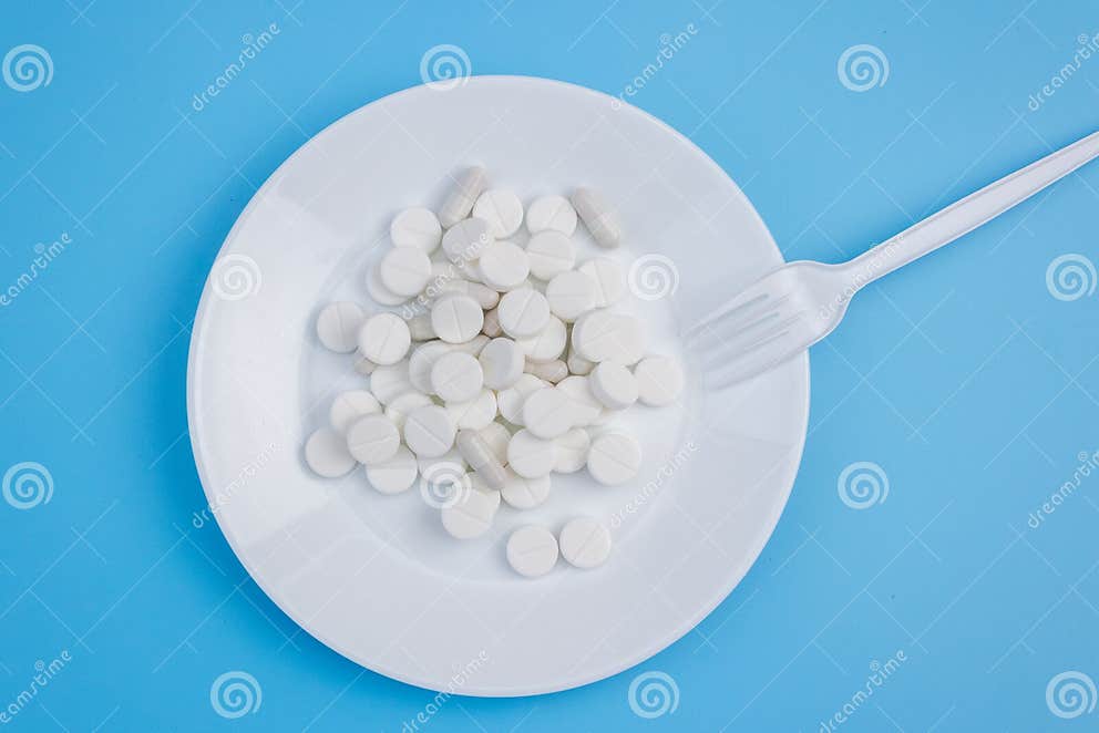 A Bunch of Medcin Tablets with a Fork on a Plate on a Blue Background ...