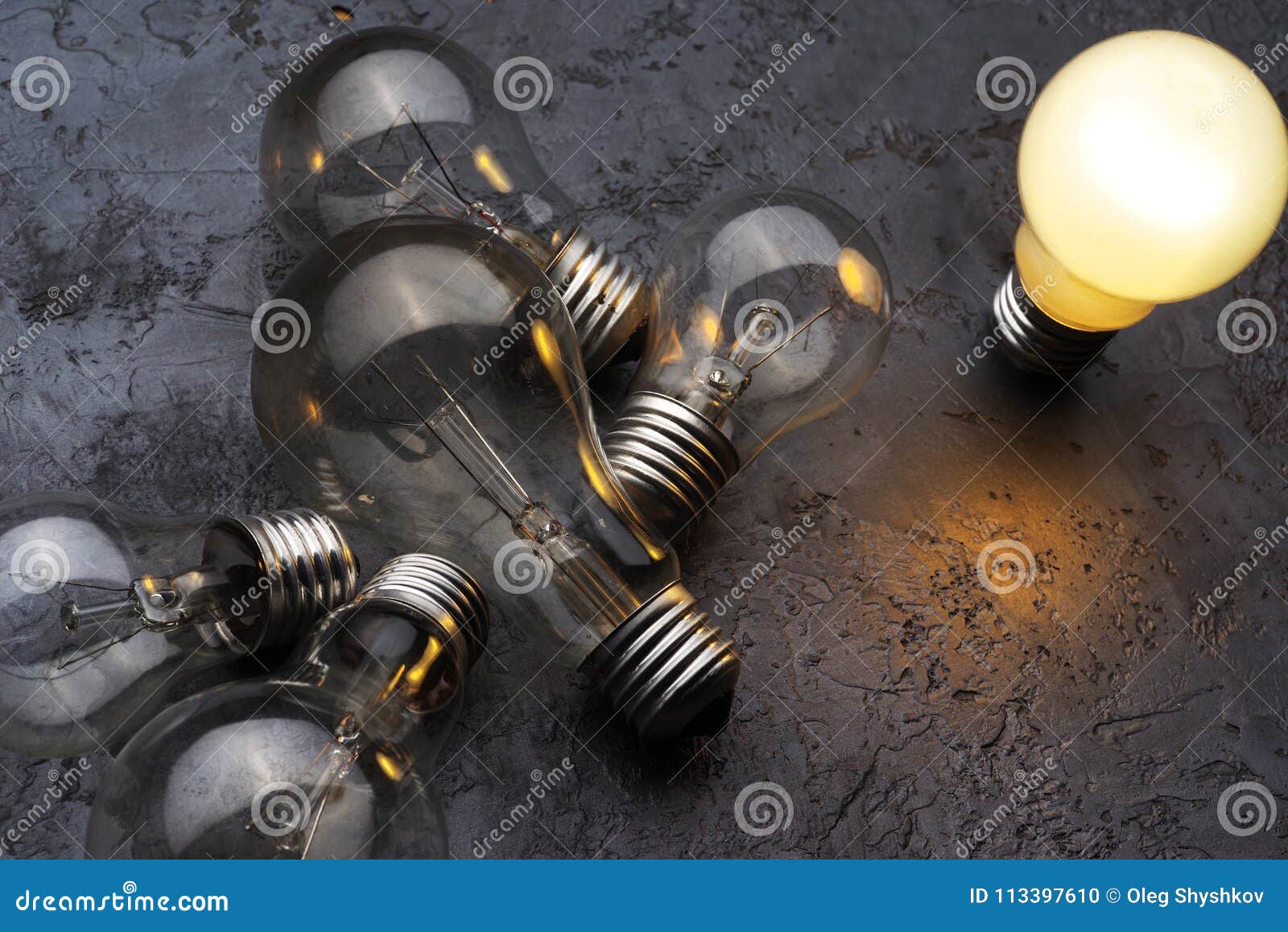 Burned Light Bulbs and One Light Bulb on a Gray Concrete Background ...