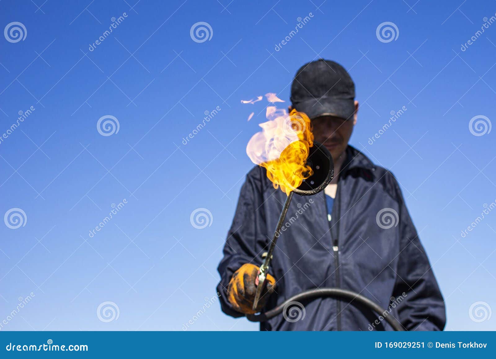 A Burner with a Fire on a Blurred Background of a Working Roofer in ...