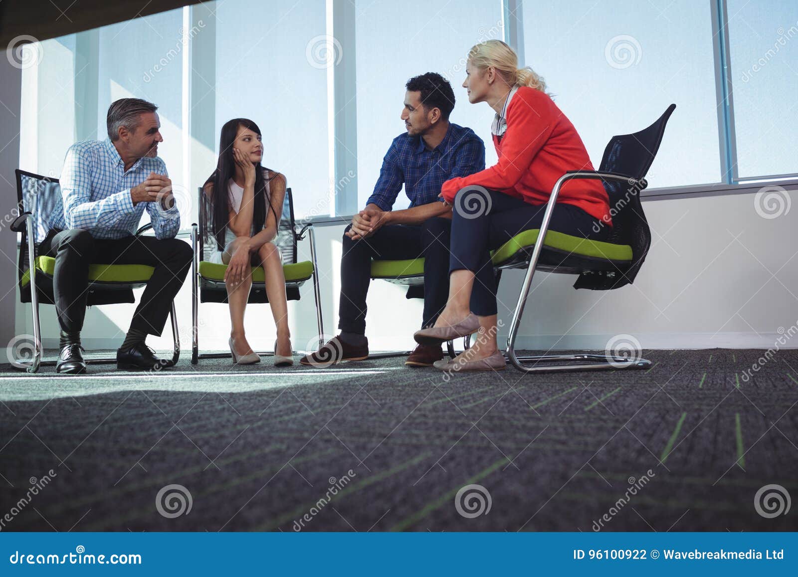 Business Colleagues Communicating while Sitting on Chairs at Office ...