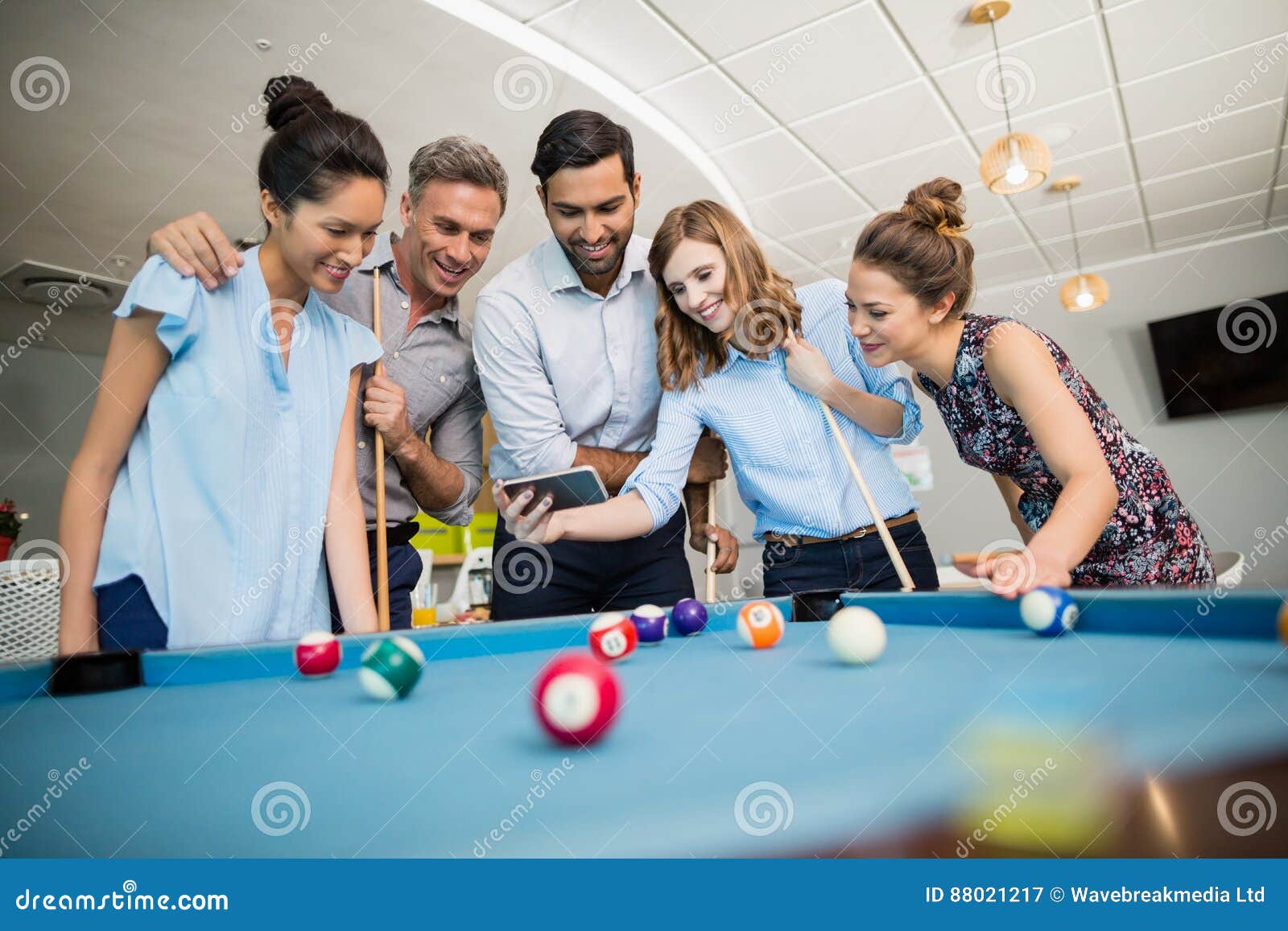 Business Colleagues Using Mobile Phone while Playing Pool in Office ...