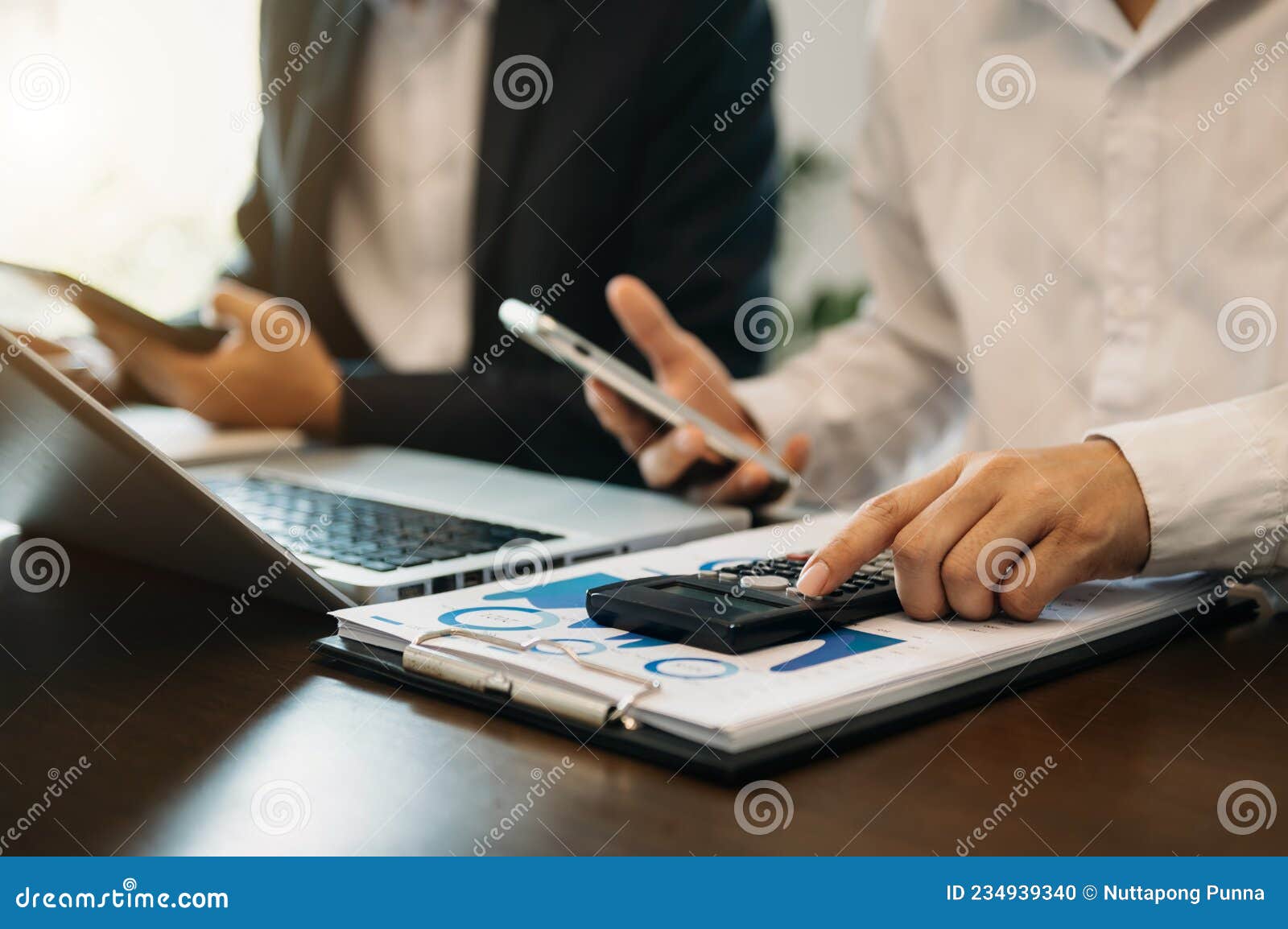 Business Documents on Office Desk with Tablet, Graph and Two Colleagues ...