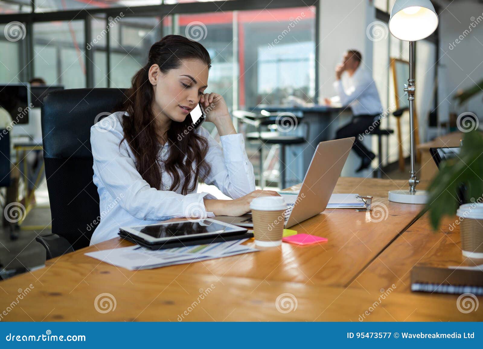 Business Executive Talking on Mobile Phone while Using Laptop at Desk ...