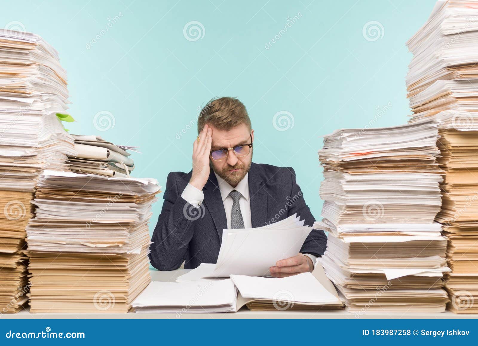 Business Executive Working in the Office and Piles of Paperwork, he is ...