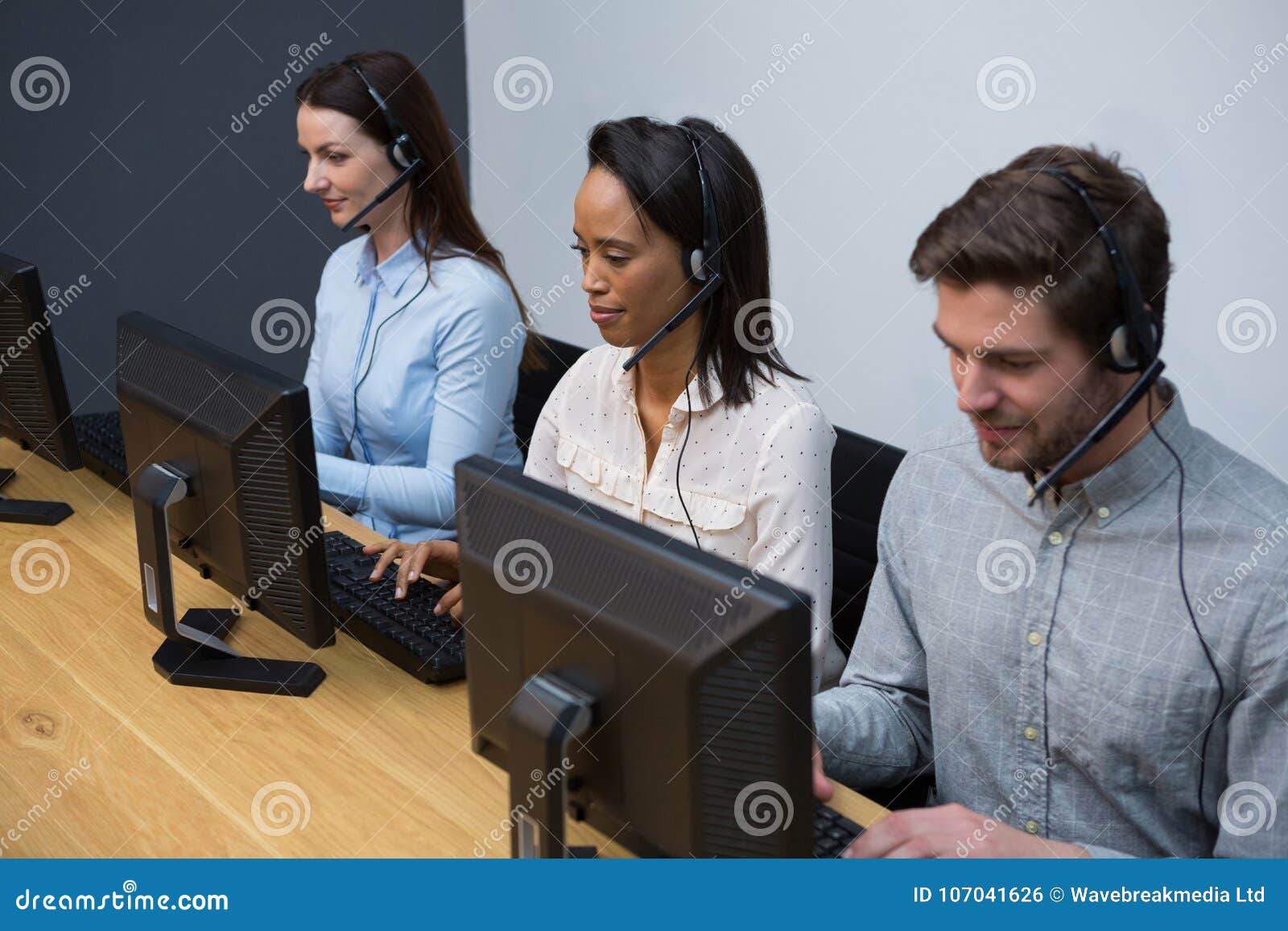 Business Executives with Headsets Using Computers at Desk Stock Photo ...