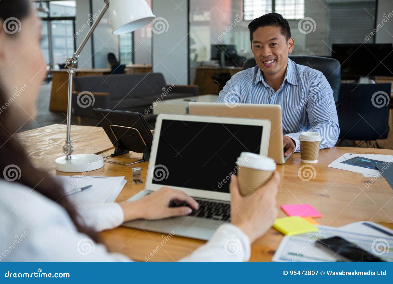 Business Executives Interacting with Each Other while Using Laptop at ...