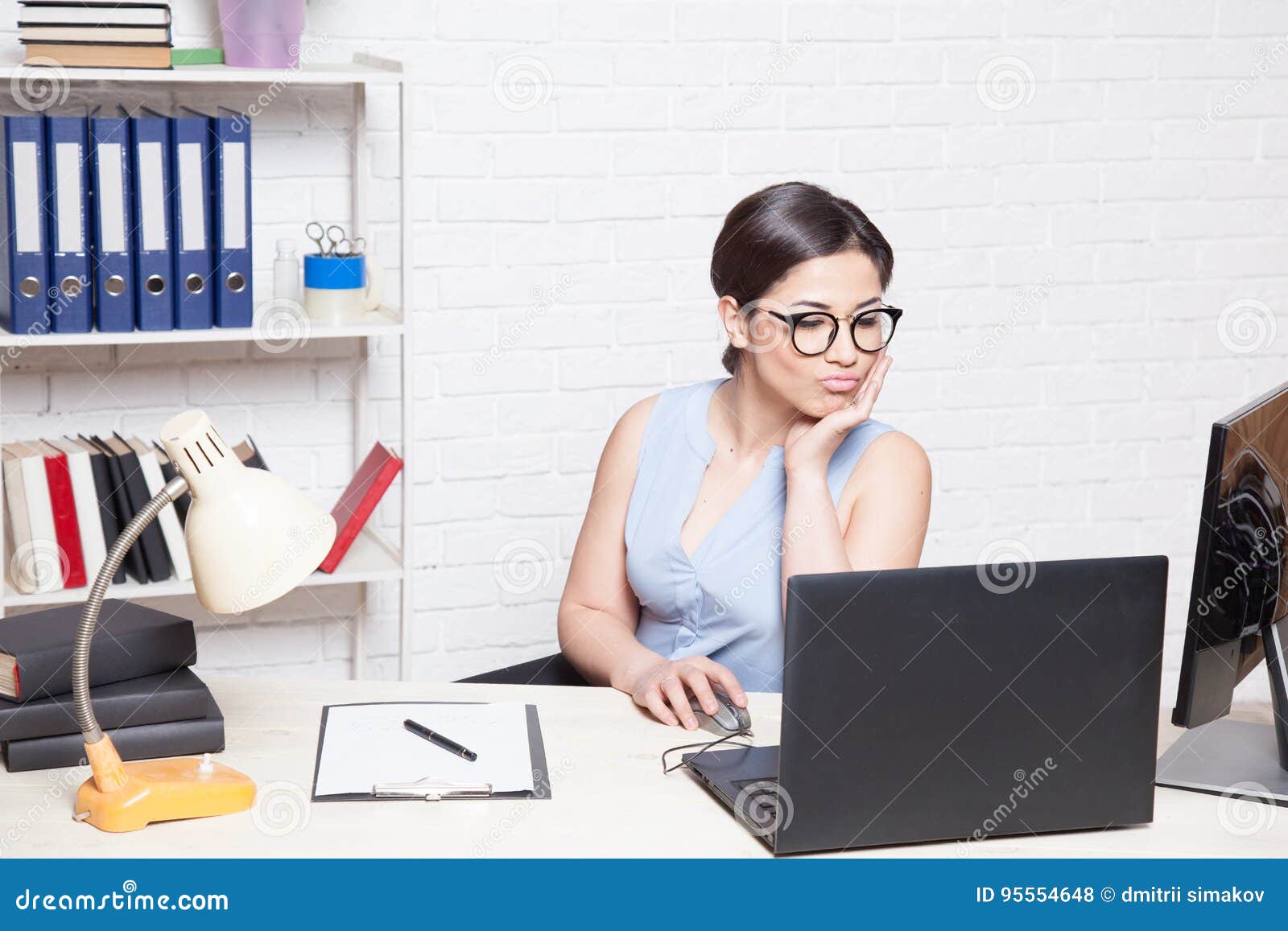 Business Girl Sits In An Office Behind A Desk With A Computer Stock