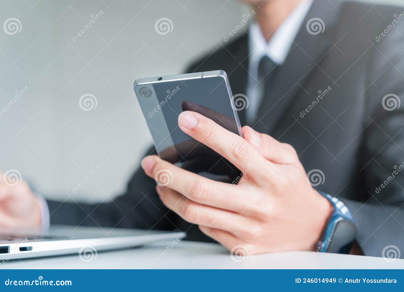 Business Man Looking at Mobile Phone while Noting Down on Notebook with ...