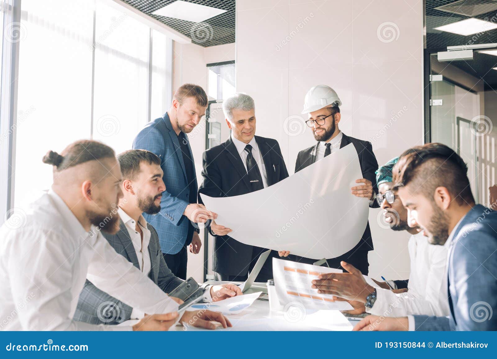 Multiracial Group of Constructors and Architects Discussing Blueprint ...