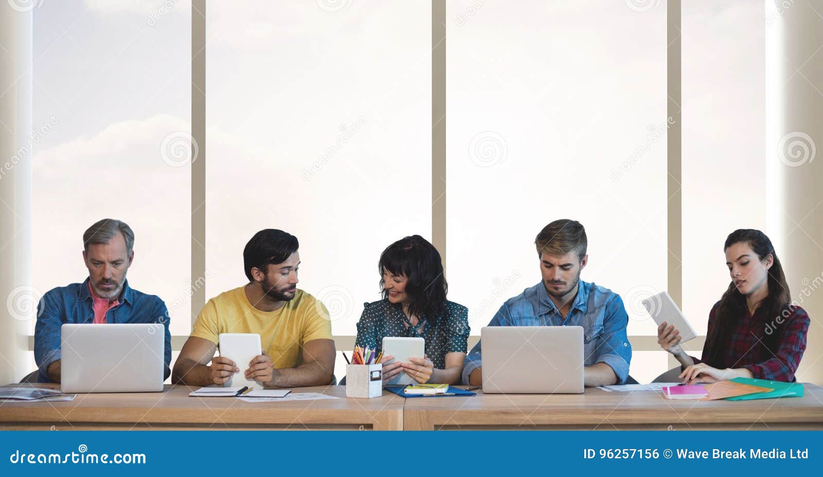 Business People at a Desk Looking at Computers and Tablets Stock Photo ...