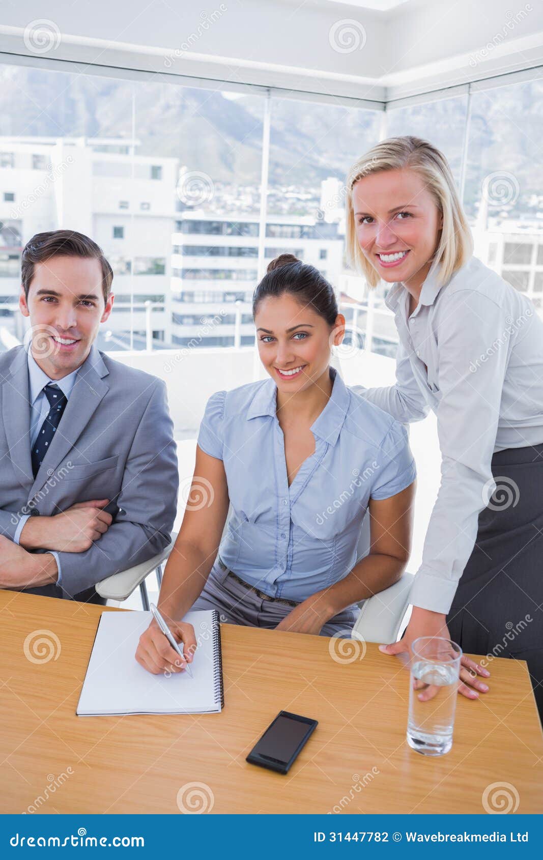 Business People at Desk with Notepad Smiling at Camera Stock Photo ...