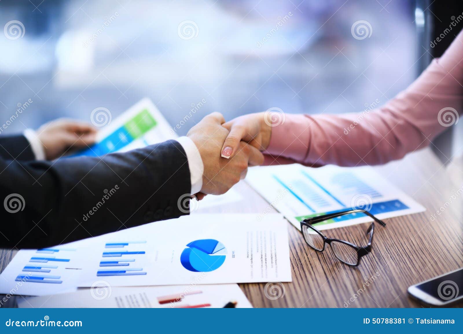 Two People Shaking Hands And Exchanging Documents As A Sign Of ...