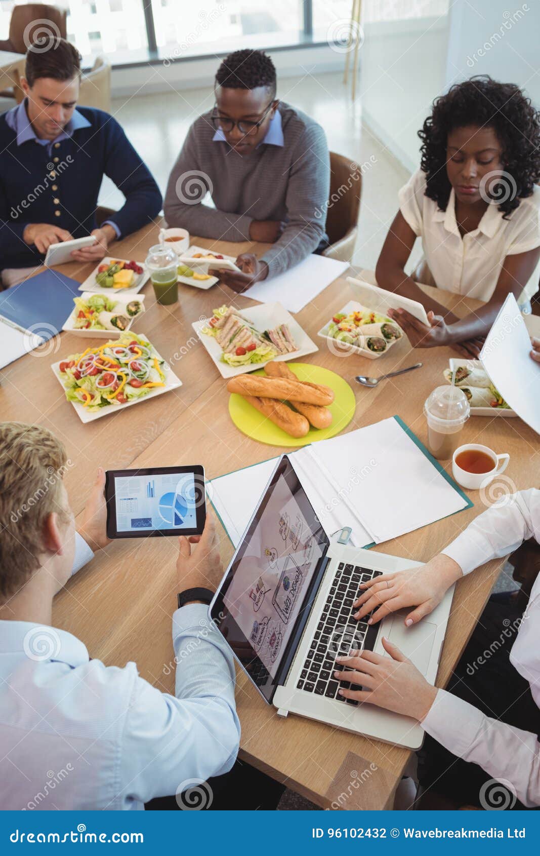 Business People Using Laptop and Digital Tablets Around Breakfast Table ...