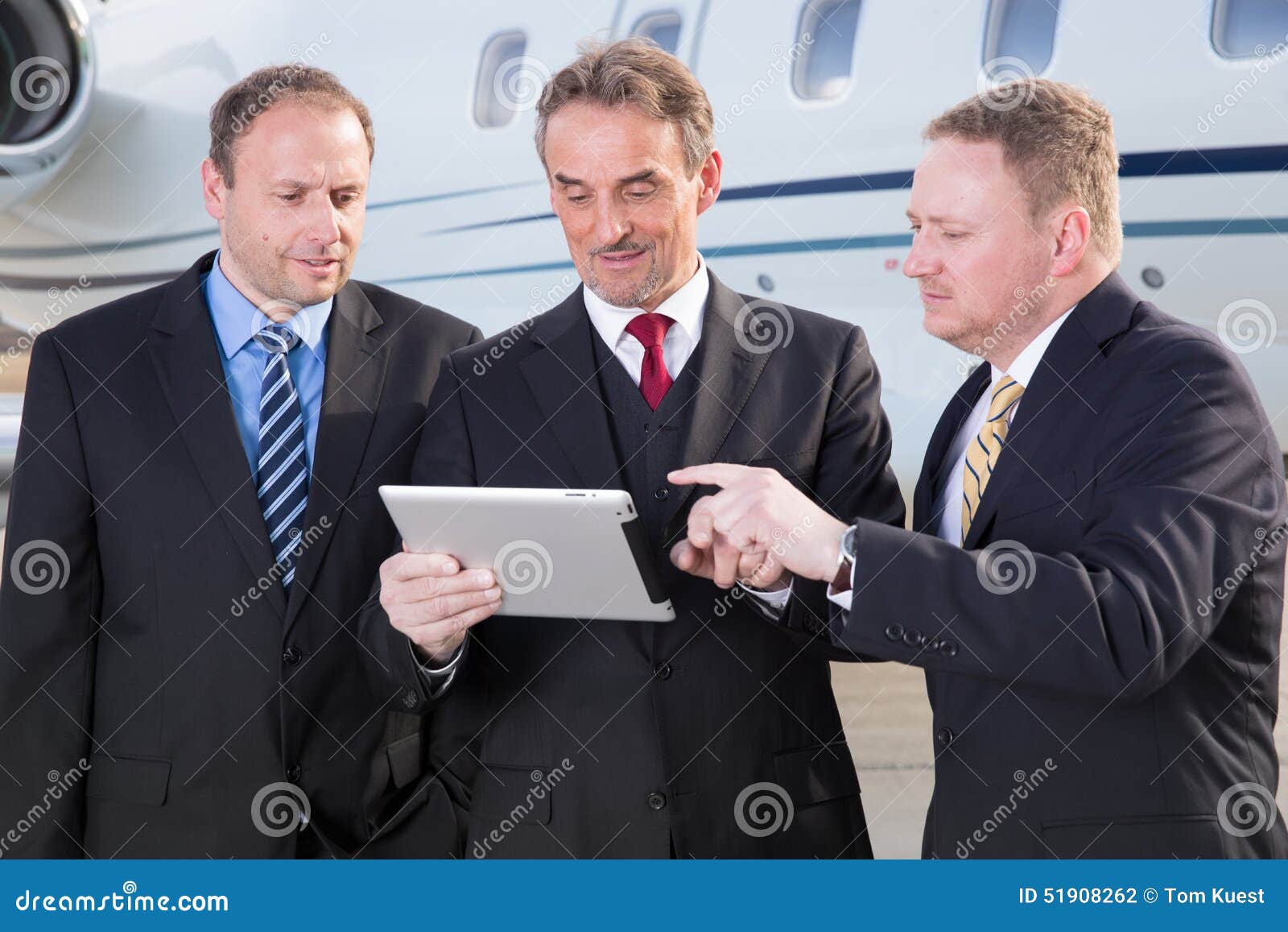 Business Team in Front of Corporate Jet Looking at Tablet Comput Stock ...