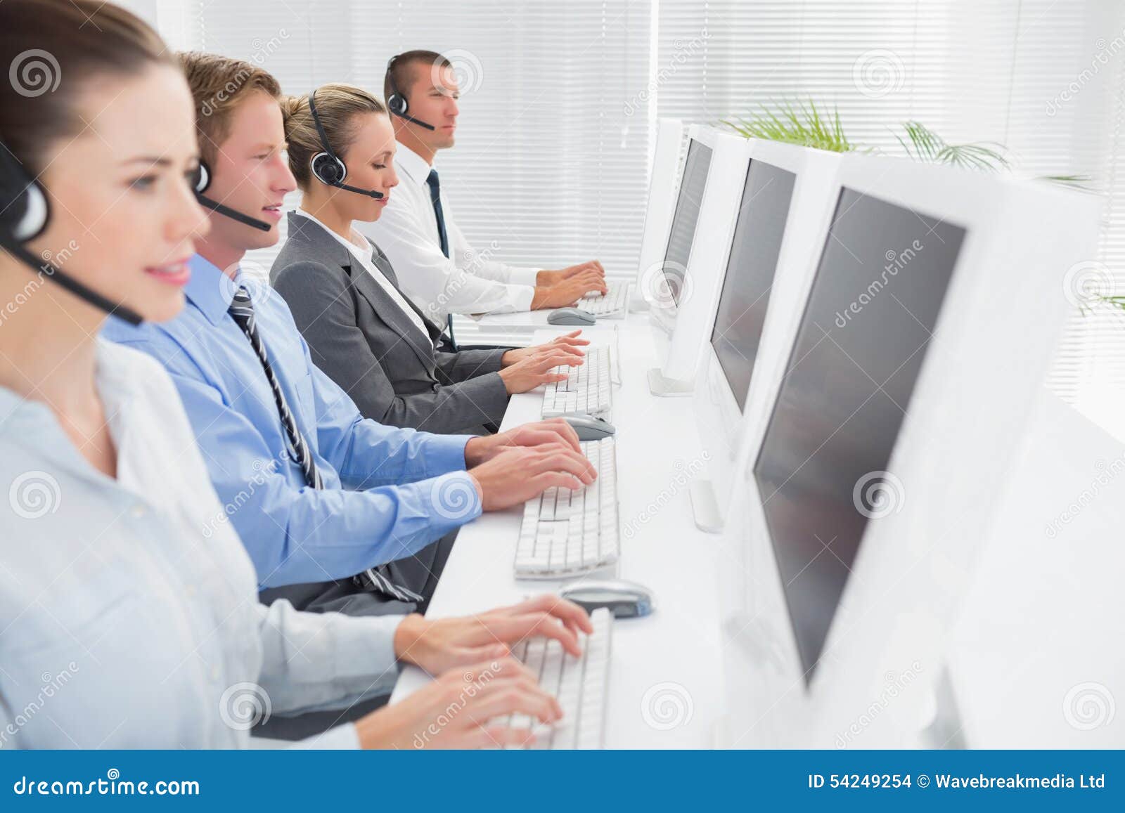Business Team Working on Computers and Wearing Headsets Stock Photo ...