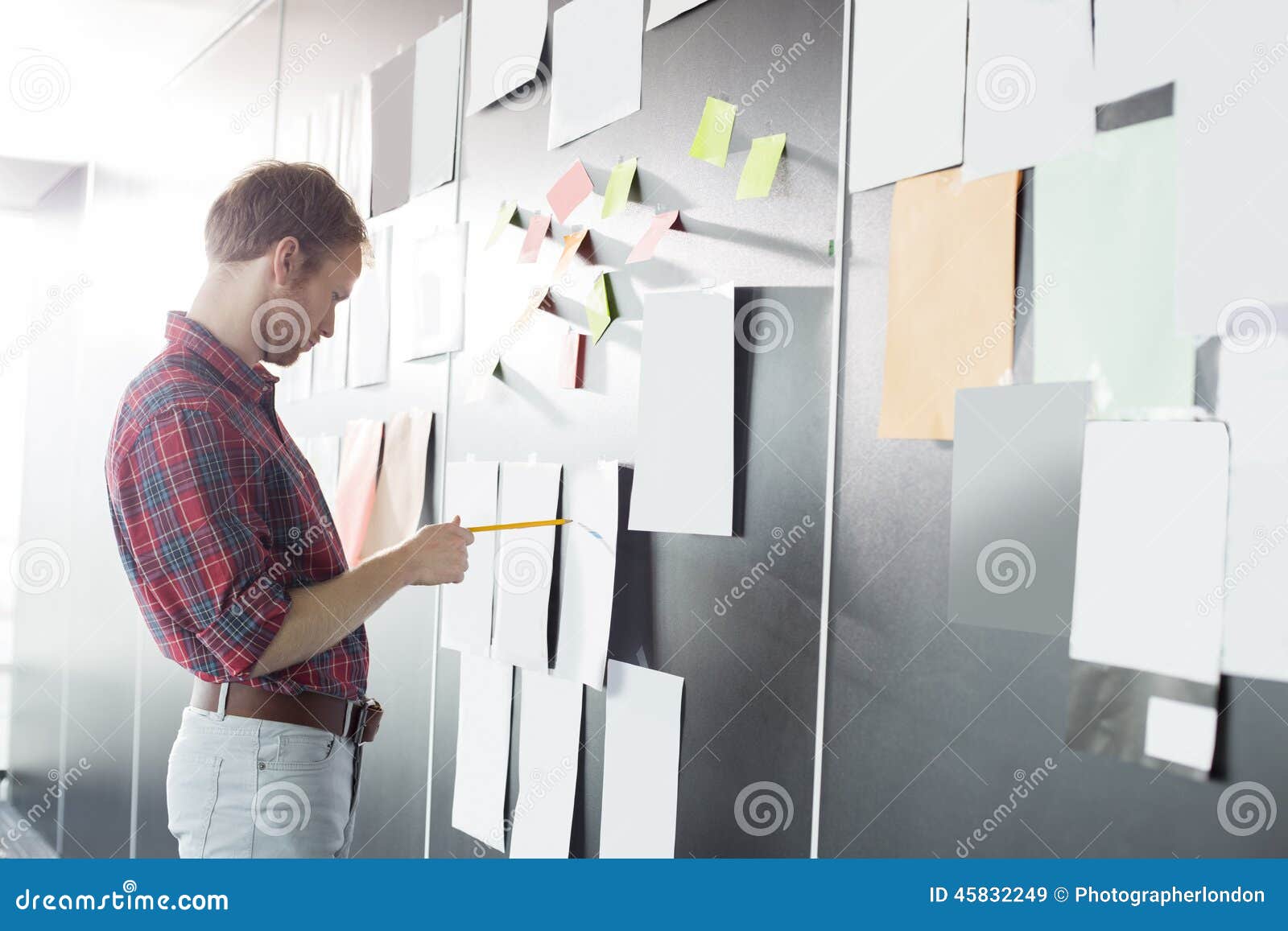 Businessman Analyzing Documents on Wall at Creative Office Stock Image ...