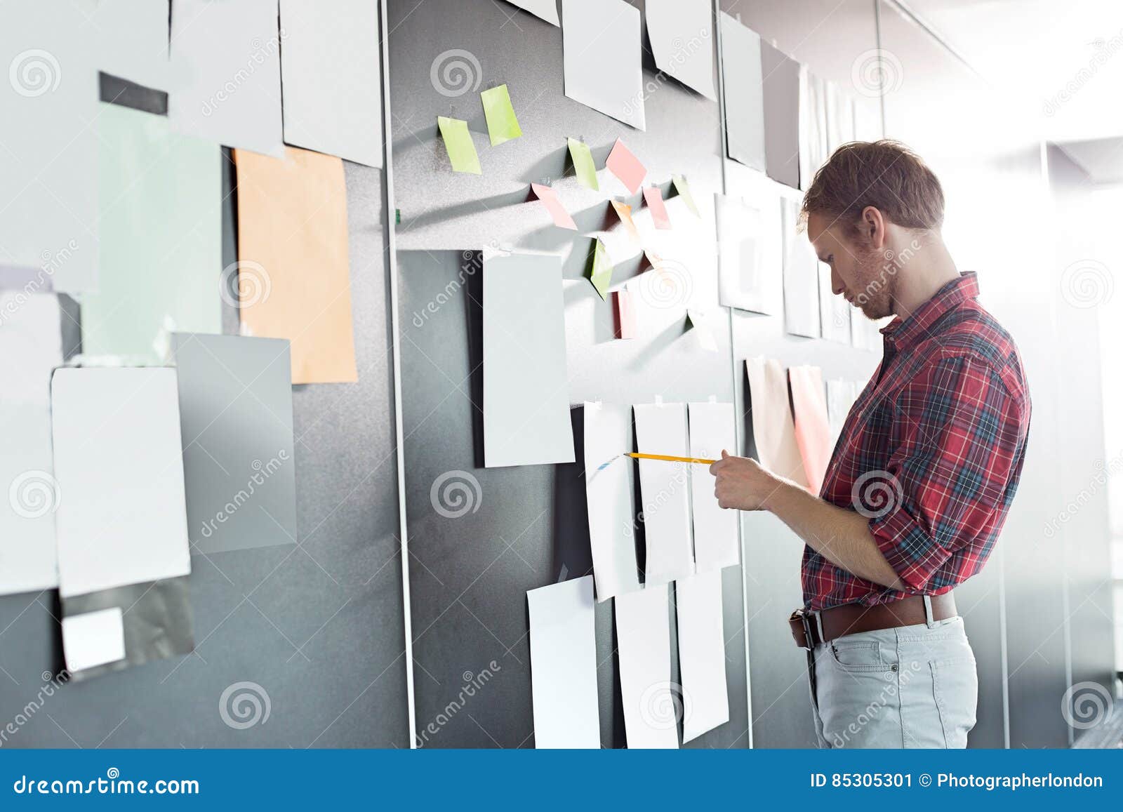 Businessman Analyzing Documents on Wall at Creative Office Stock Image ...