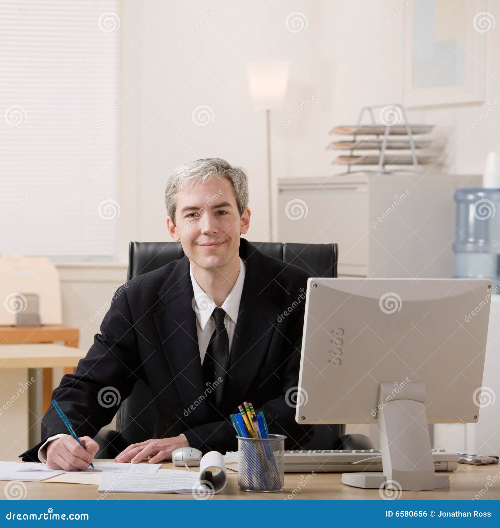 Businessman Filling Out Paperwork at Desk Stock Photo - Image of ...