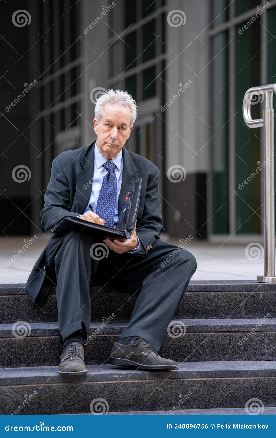 Businessman Going Over His Notes while Sitting on an Office Building ...