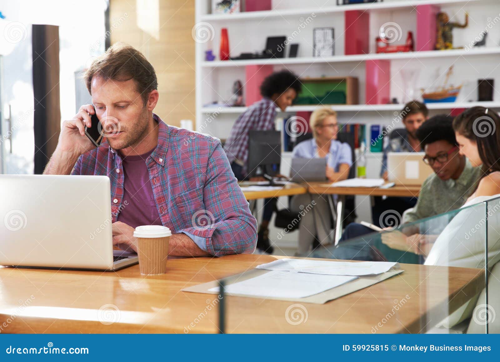 Businessman on Laptop Using Mobile Phone in Busy Office Stock Image ...
