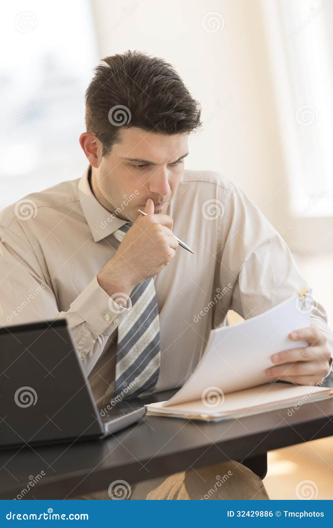 Businessman Looking at Documents while Sitting at Desk in Office Stock ...