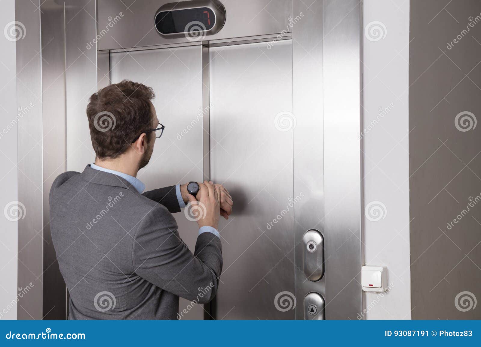 Businessman Looking at His Watch while Waiting for the Elevator Stock ...