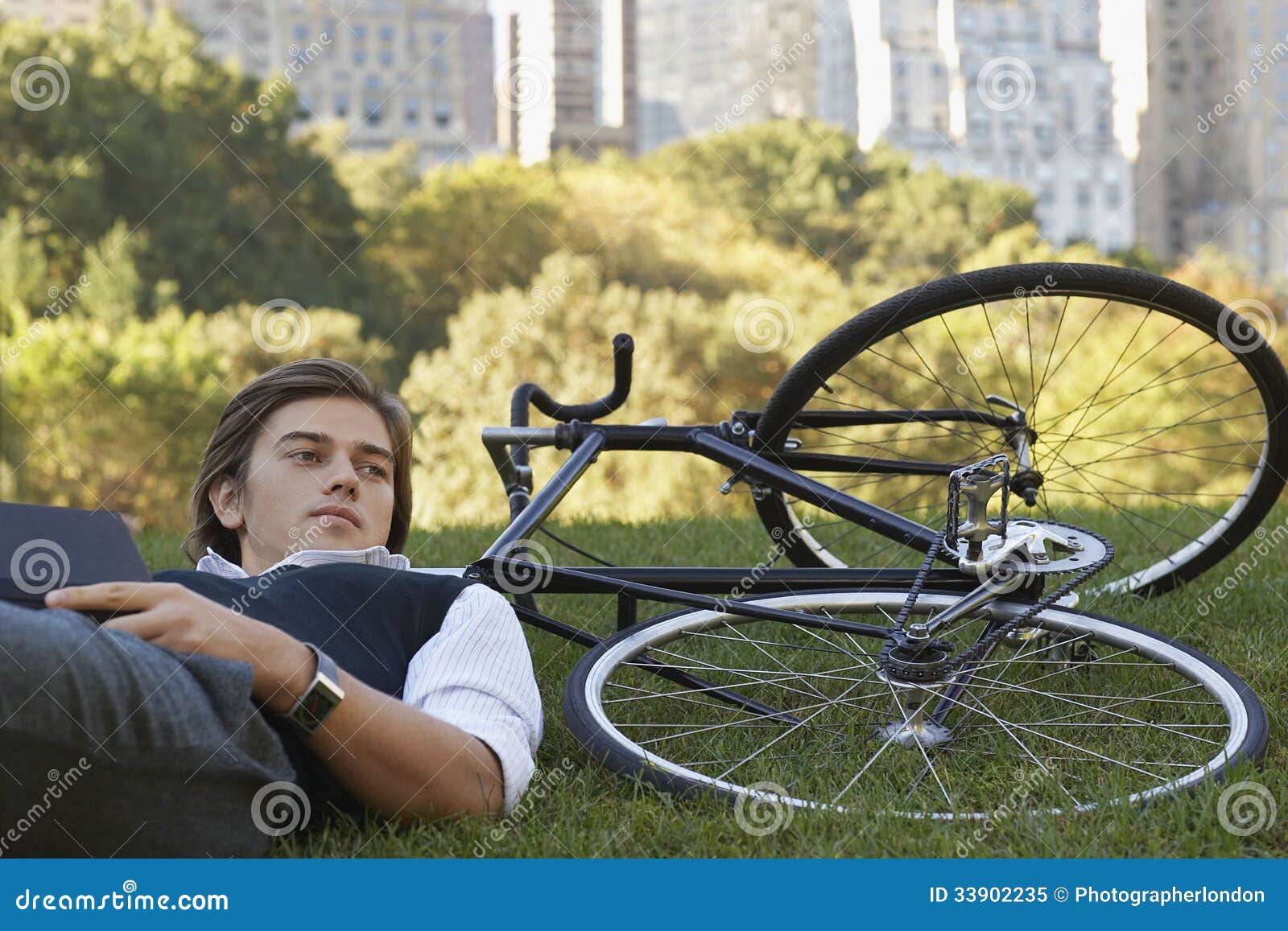 Businessman Lying Down on Bicycle in Park Stock Image - Image of ...