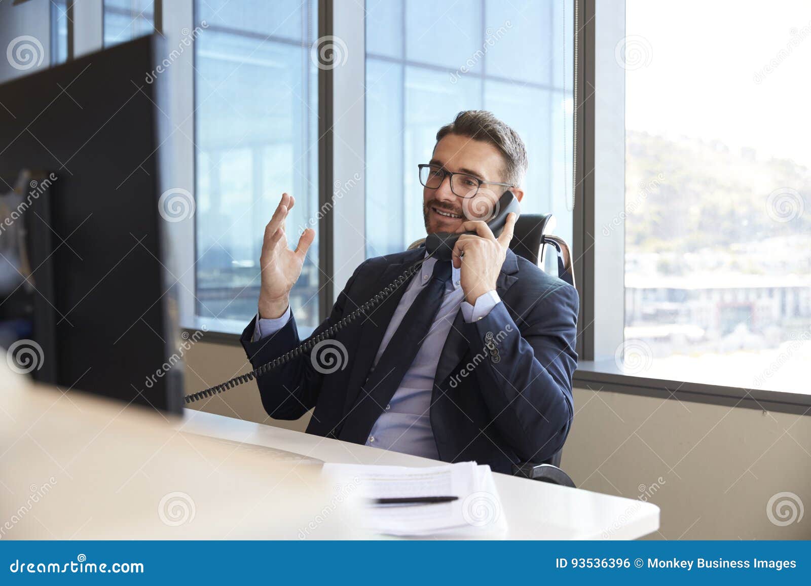 Businessman Making Phone Call Sitting at Desk in Office Stock Photo ...