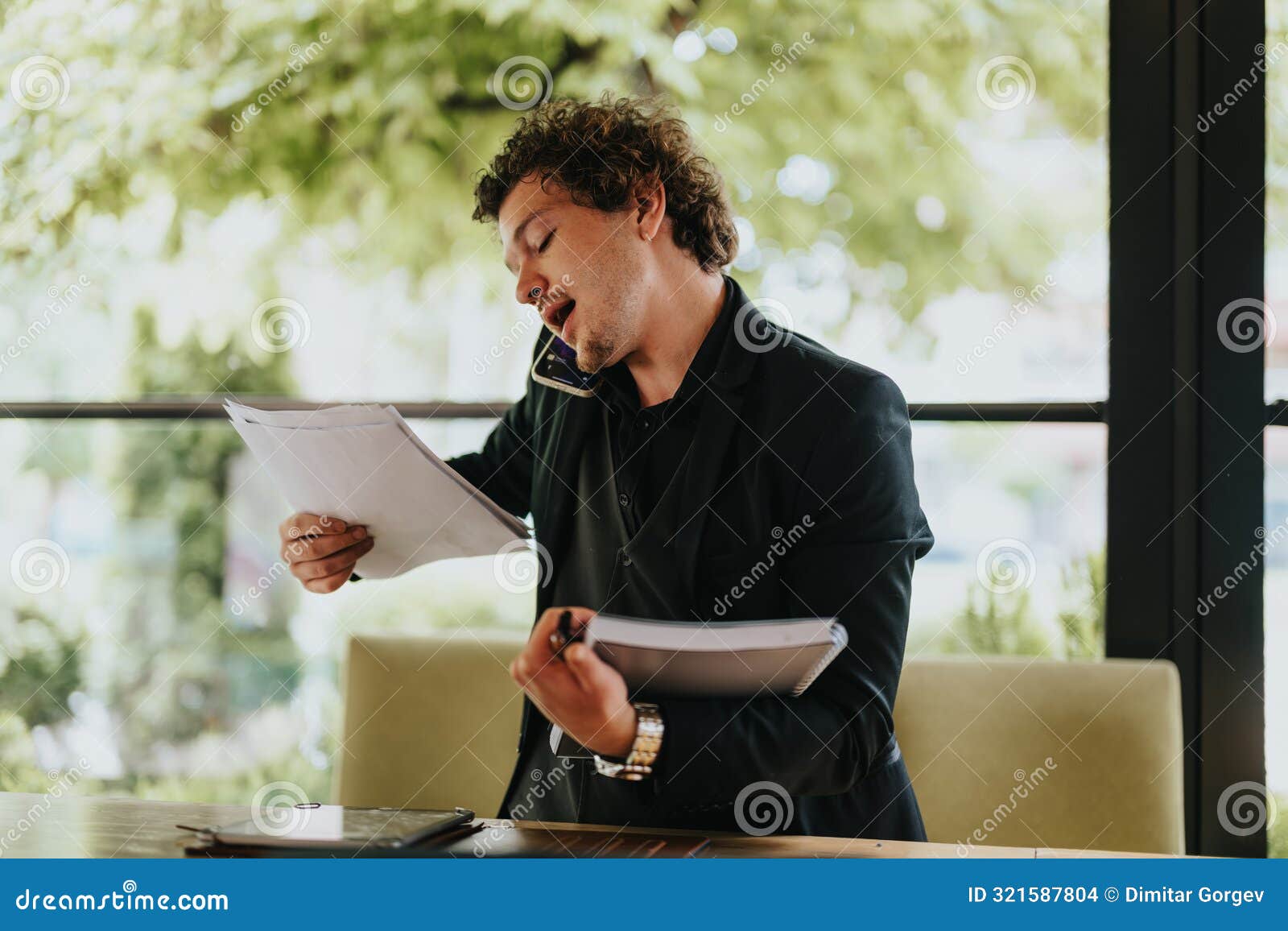 Businessman Multitasking with Documents and Phone Call in Modern Office ...