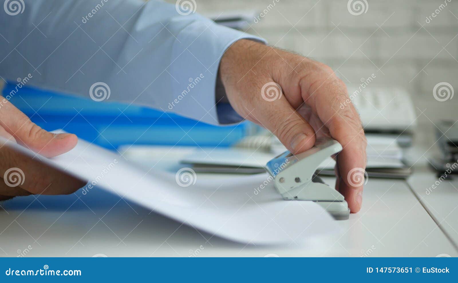 Businessman in Office Archiving Documents with a Paper Hole Puncher ...