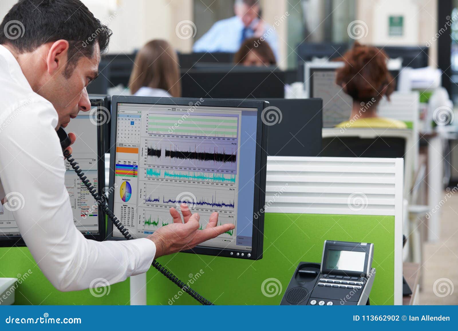Businessman on Phone Using Computer in Busy Office Stock Photo - Image ...