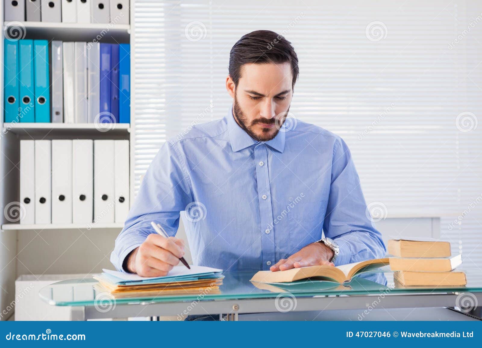 Businessman Reading Book while Writing at His Desk Stock Photo - Image ...