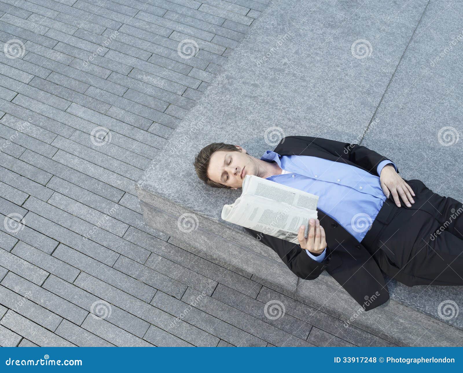 Businessman Reading Newspaper while Lying on Wall Stock Photo - Image ...