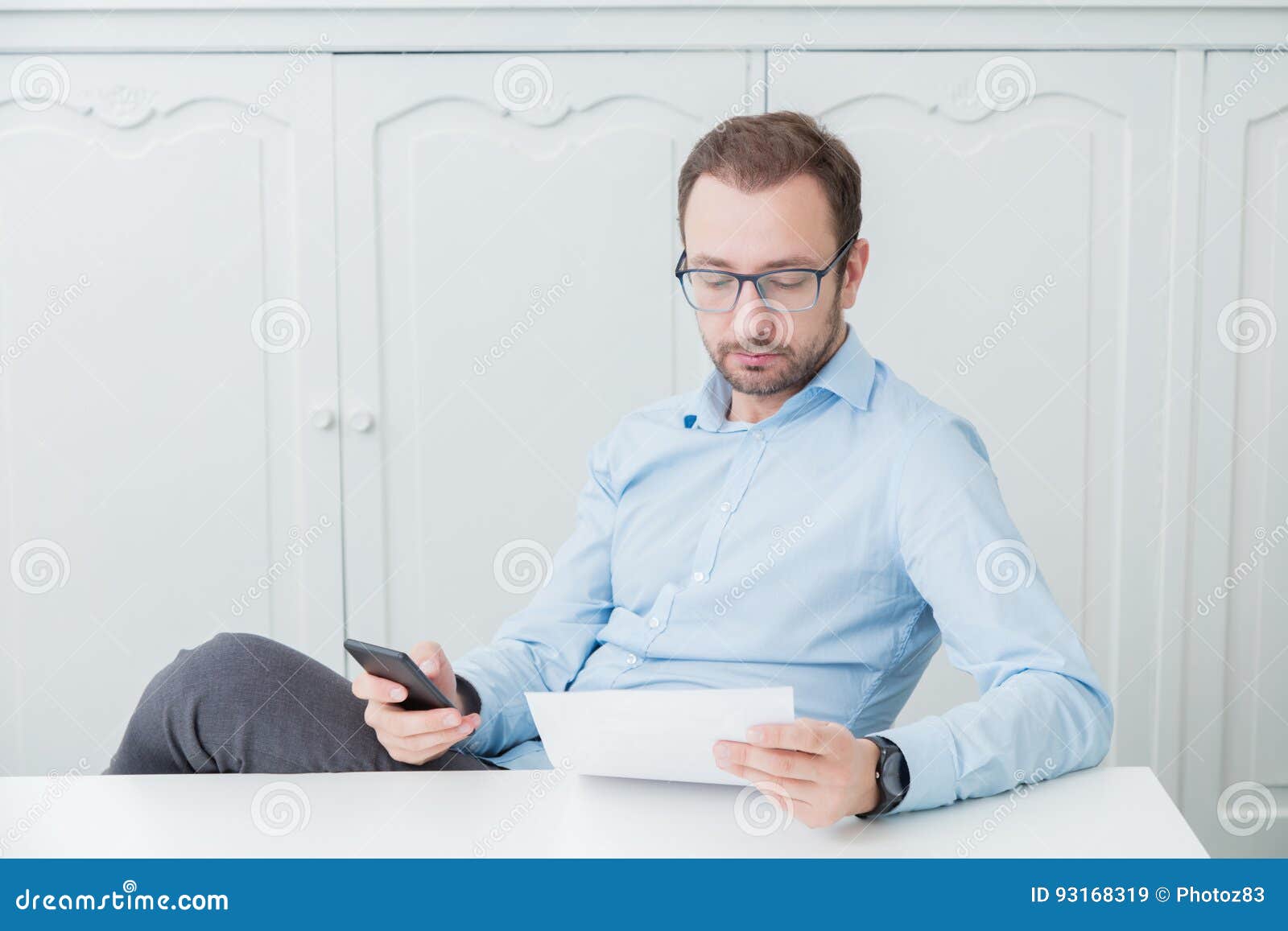 Businessman Sitting at His Desk, Looking at Paper Document and H Stock ... Businessman Sitting at His Desk, Looking at Paper Document and H Stock ...